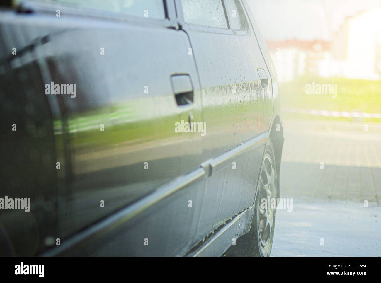 Side view of a black car with water splashes highlighting a cleaning ...