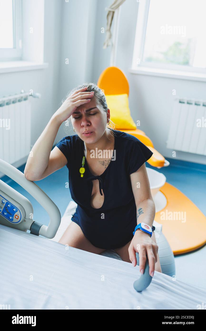 A woman in the delivery room feels contractions and severe pain in her ...