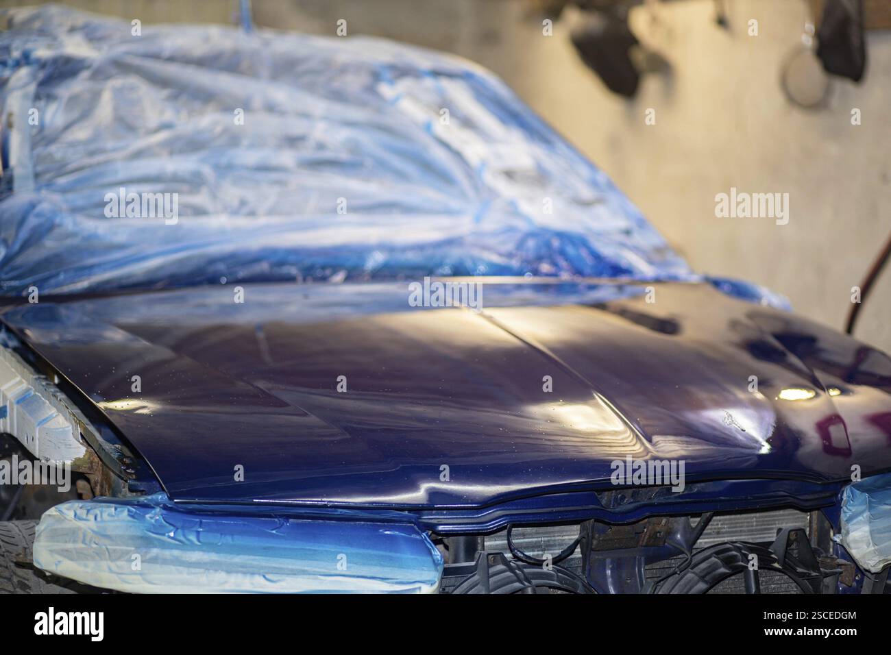 Front view of a blue car with a glossy finish, partially covered with ...