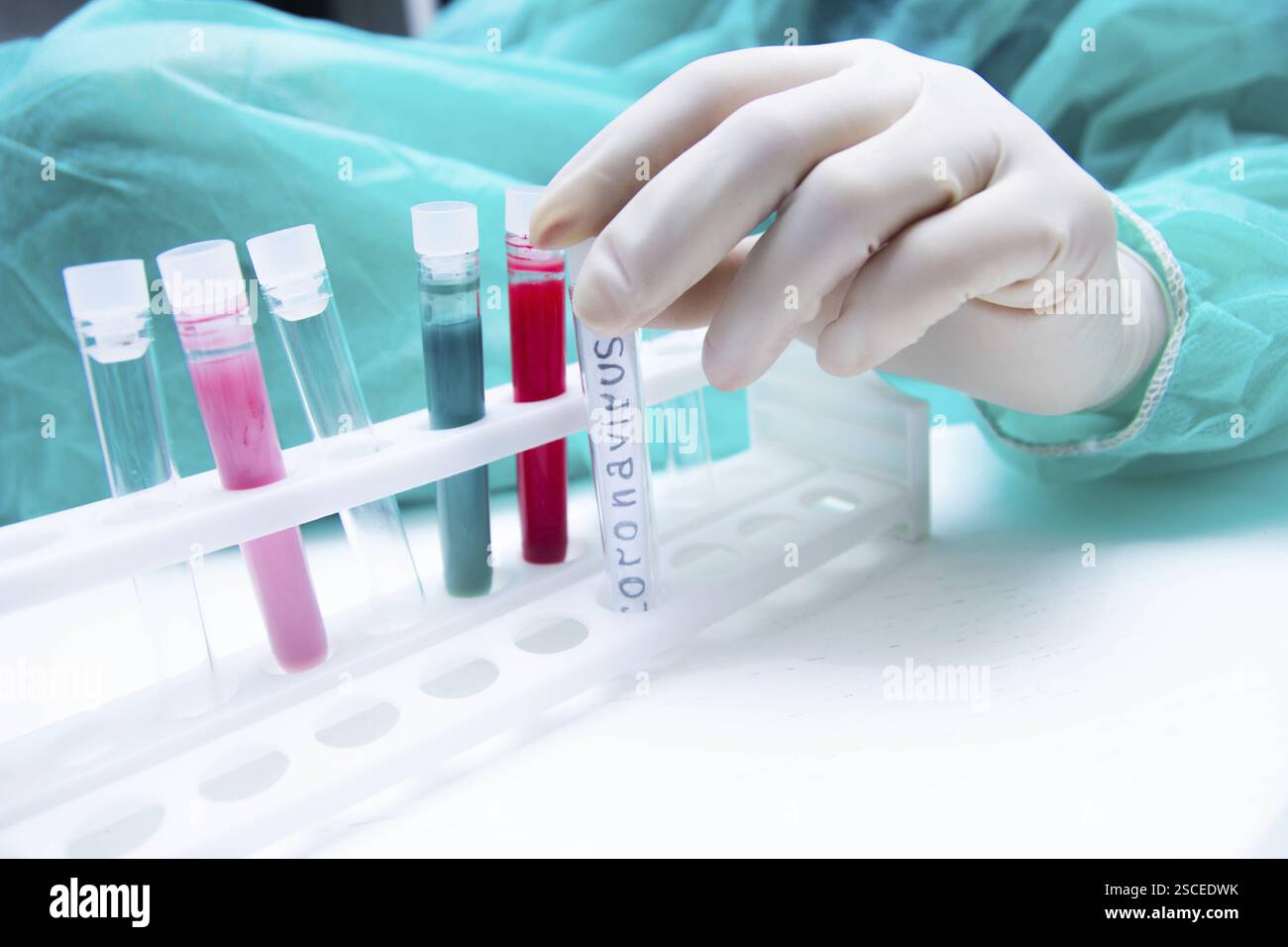 A hand placing a coronavirus-labeled tube into a rack with other ...