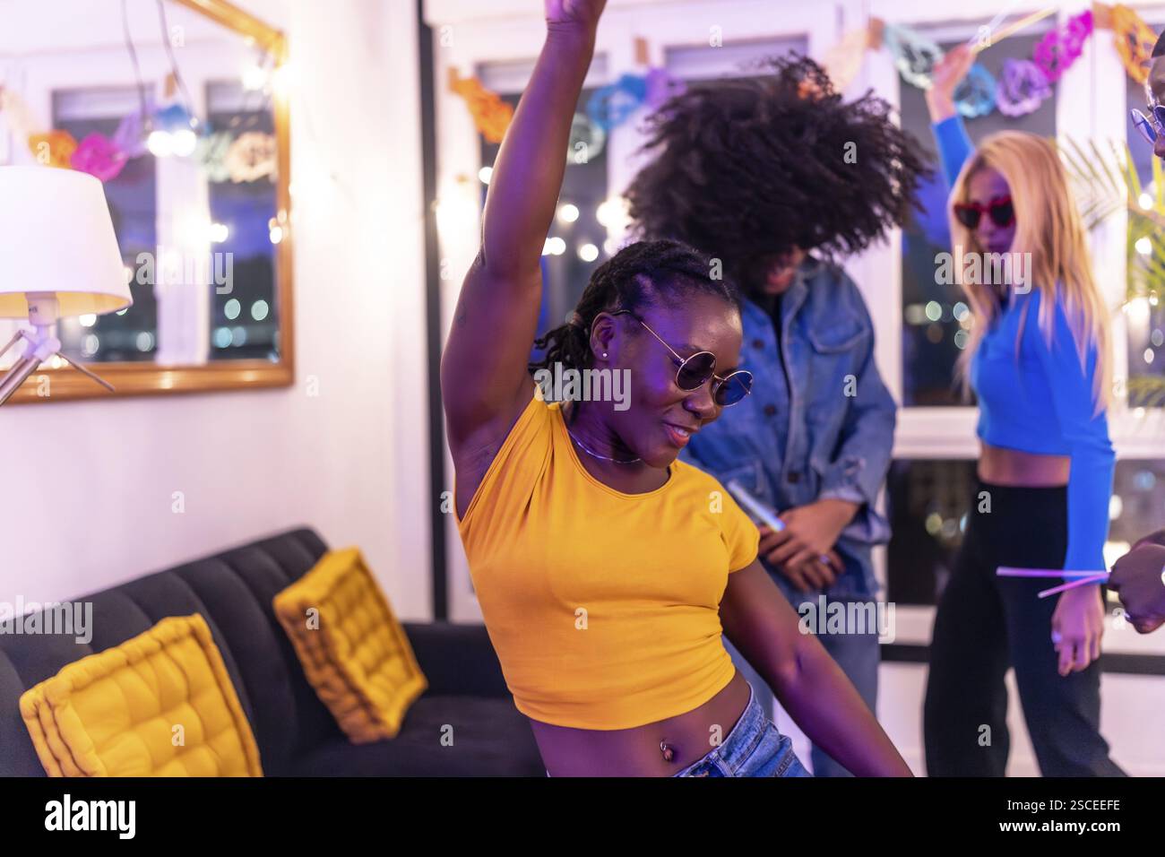 African cool woman dancing during night house party next to multi ...