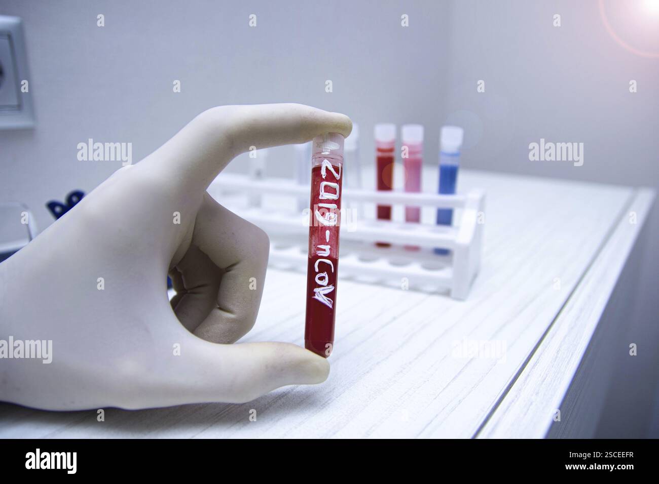 Test tube labeled 2019-nCoV held by hand with colorful tubes in lab ...