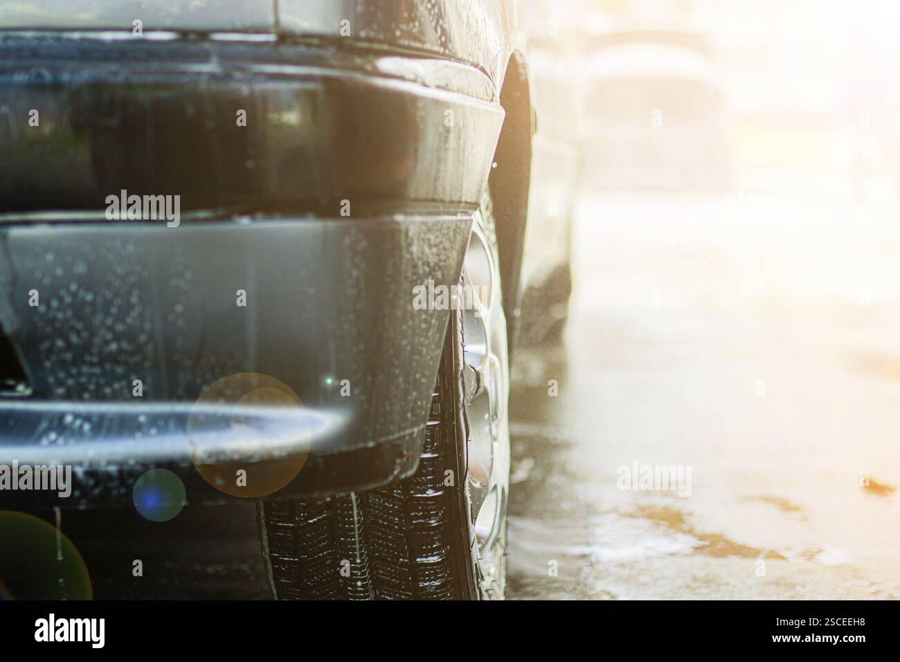 A vehicle's wet tire and body reflect sunlight at a car wash Stock ...