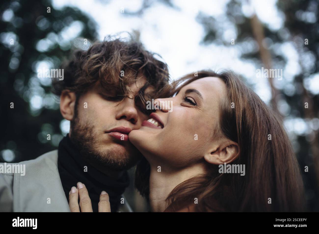 A couple embracing intimately in a forest setting, creating a romantic ...