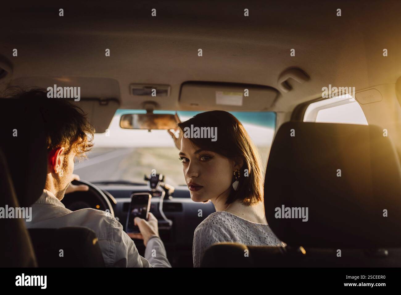 Woman looking back in a car with a man driving during sunset Stock ...