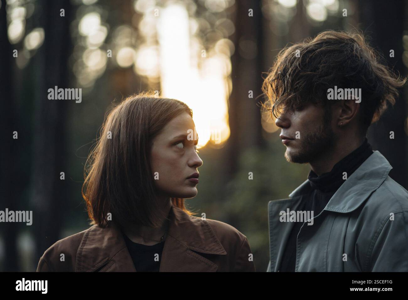 A couple makes eye contact amidst trees in a forest at sunset Stock ...