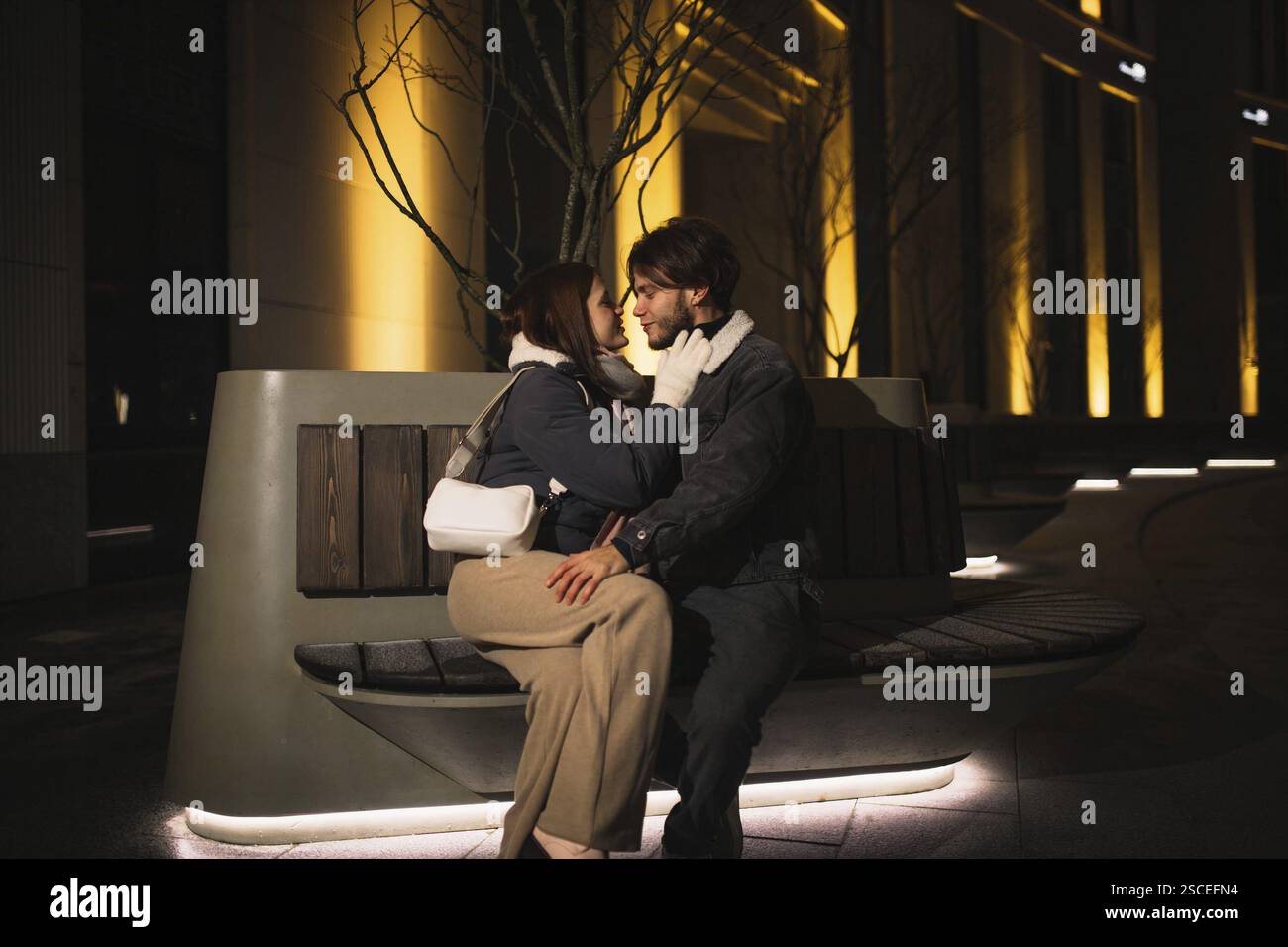 Close couple talking intimately on a bench at night in a city setting ...