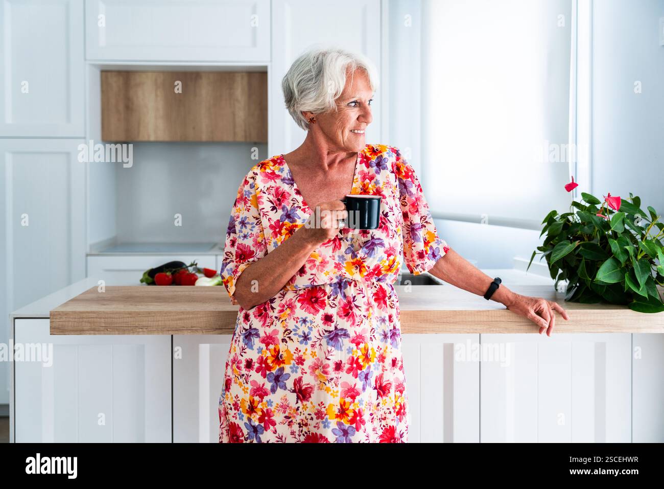 Beautiful senior old woman with gray hair drnking cup of coffee at home ...