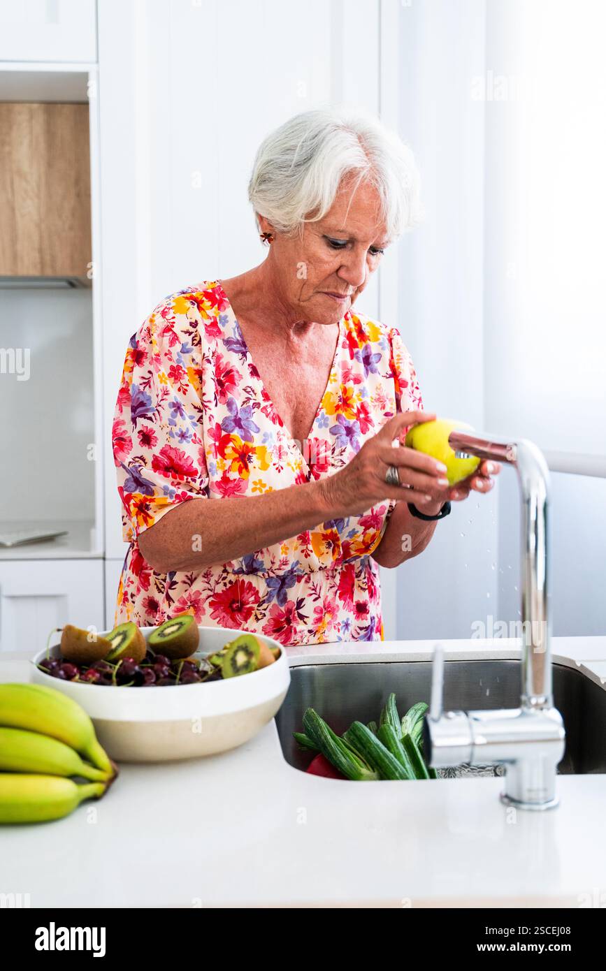Beautiful senior old woman with gray hair eating fruits at home ...