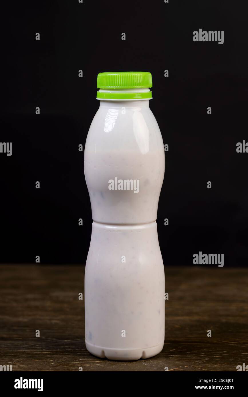 one white plastic bottle for milk and dairy products on a black ...