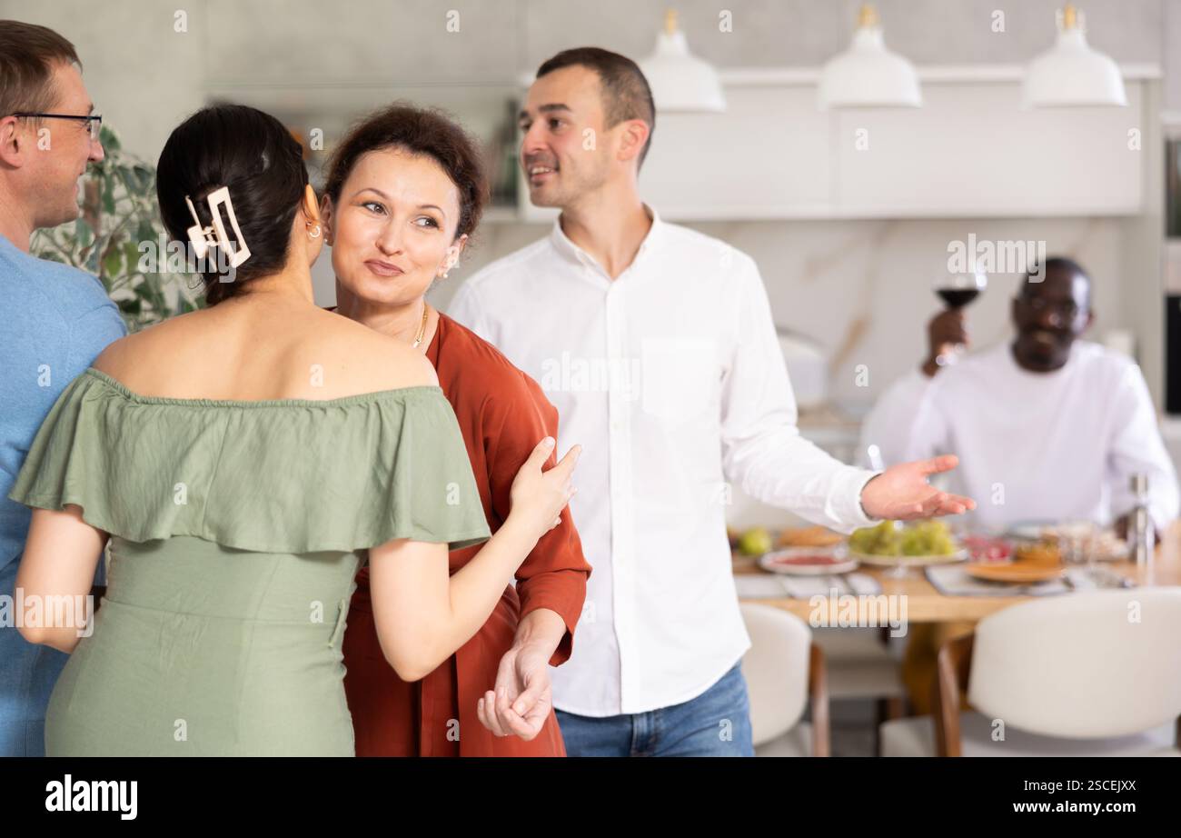 Smiling woman hostess hugging and kissing guest at dinner party Stock ...