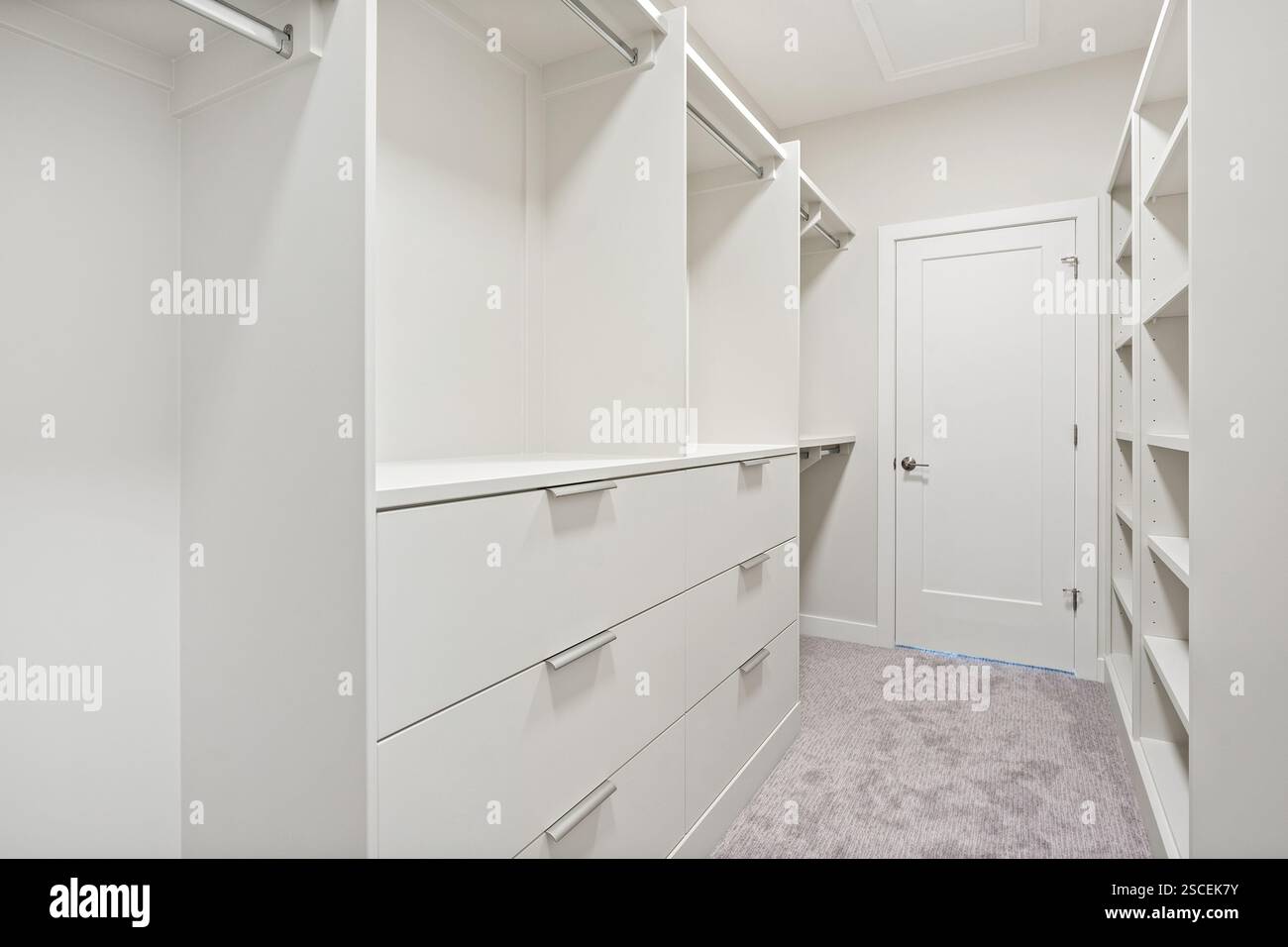A white walk in closet with shelves and drawers. The closet is very ...
