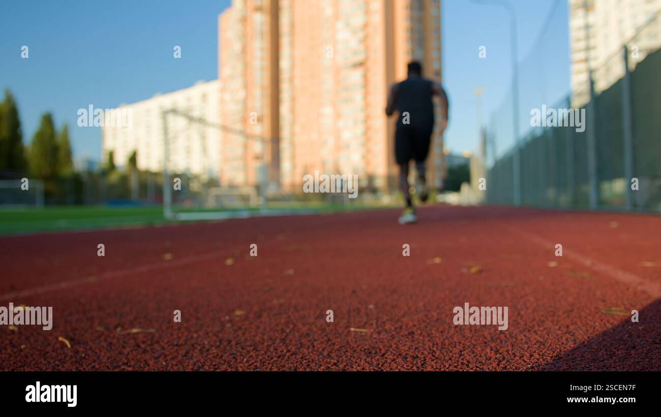 Back view runner in low start position on stadium running track male ...