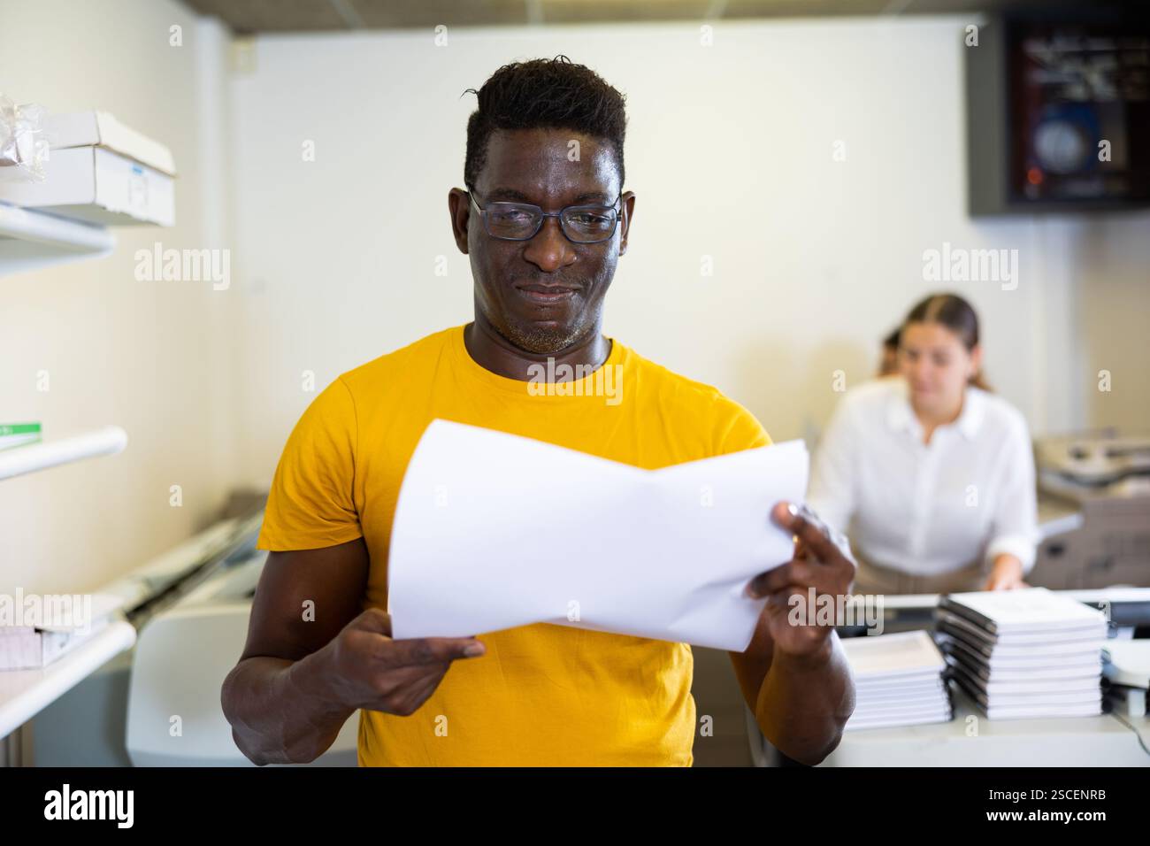 Focused African American man checking the print quality and accepting ...