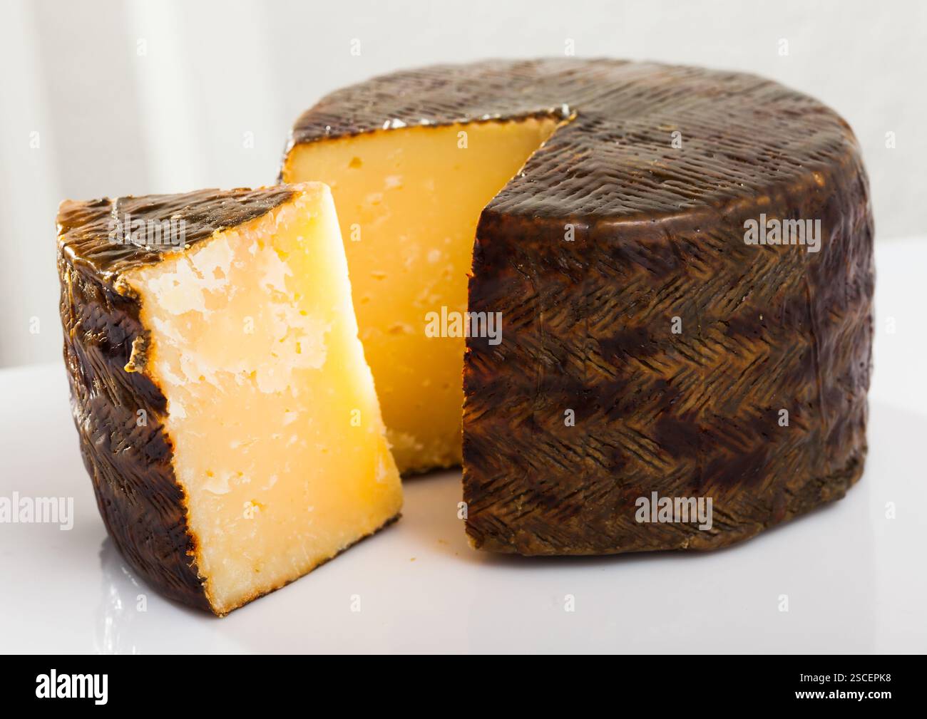 Wheel of cheese Manchego with cut slice Stock Photo - Alamy