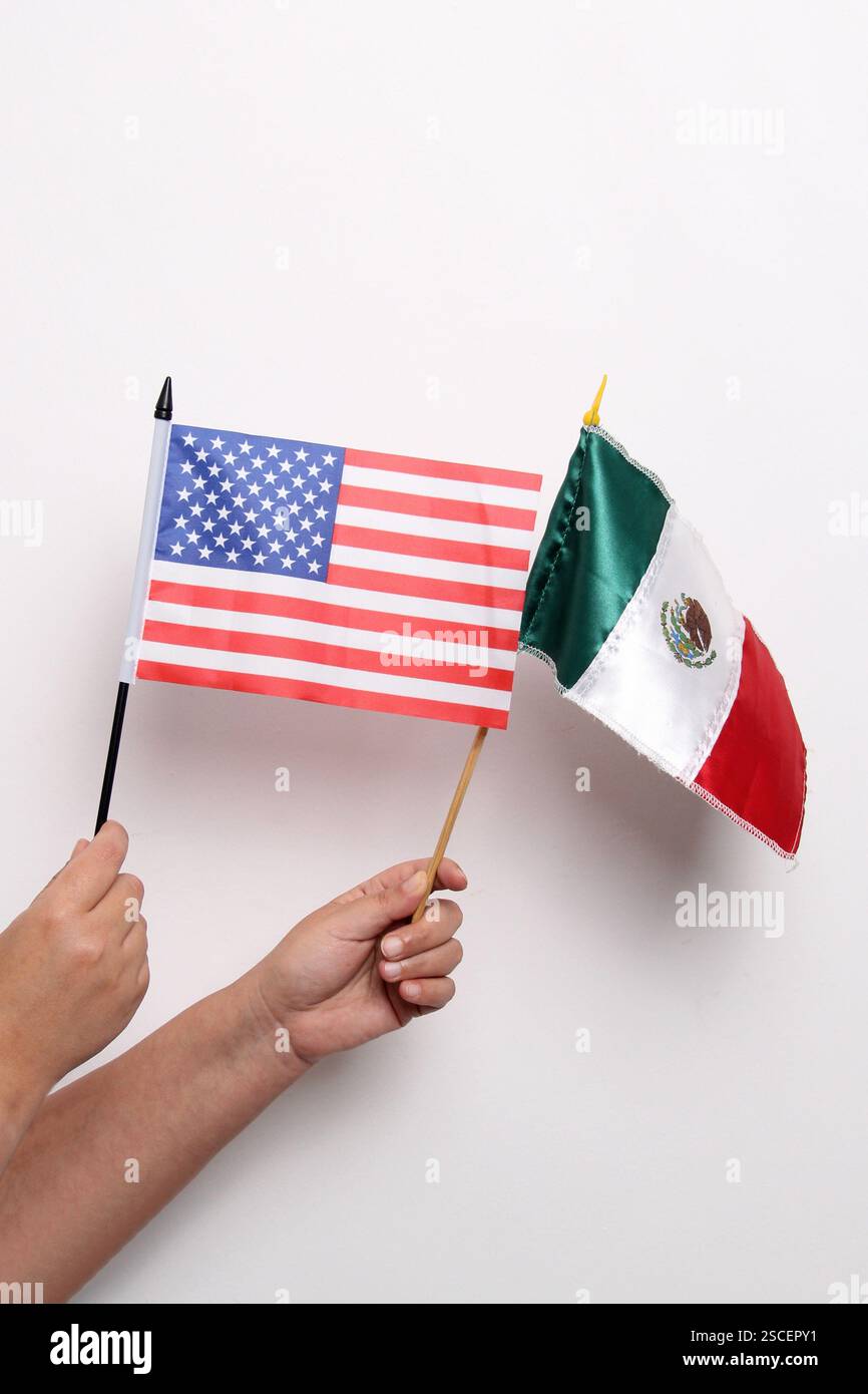 Hands holding flags of Mexico and the United States as a representation ...