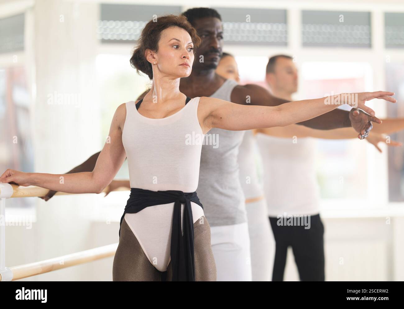 Woman mastering second ballet position at barre in choreographic studio ...
