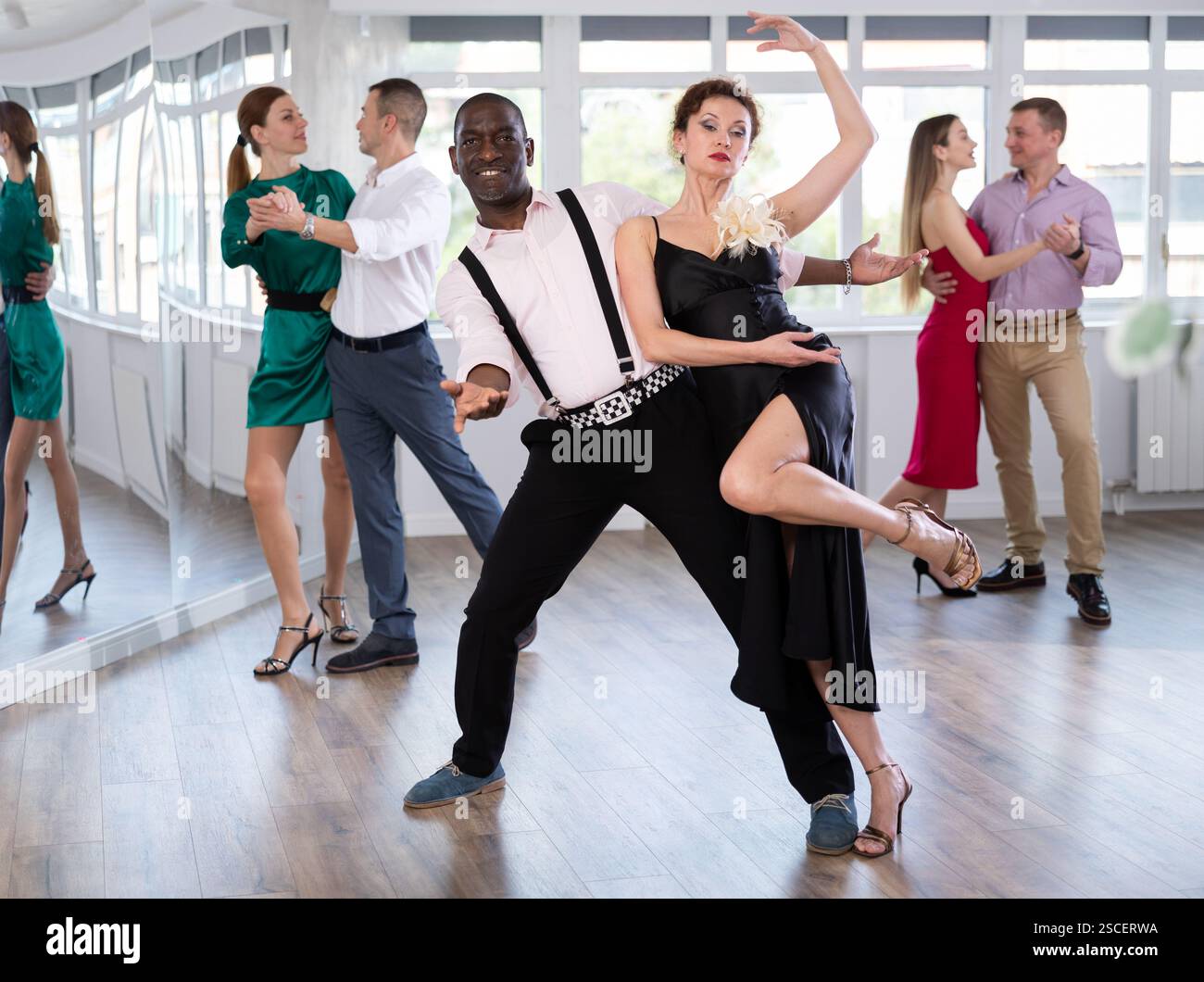Woman with African man dancing waltz in couple during lesson at studio ...