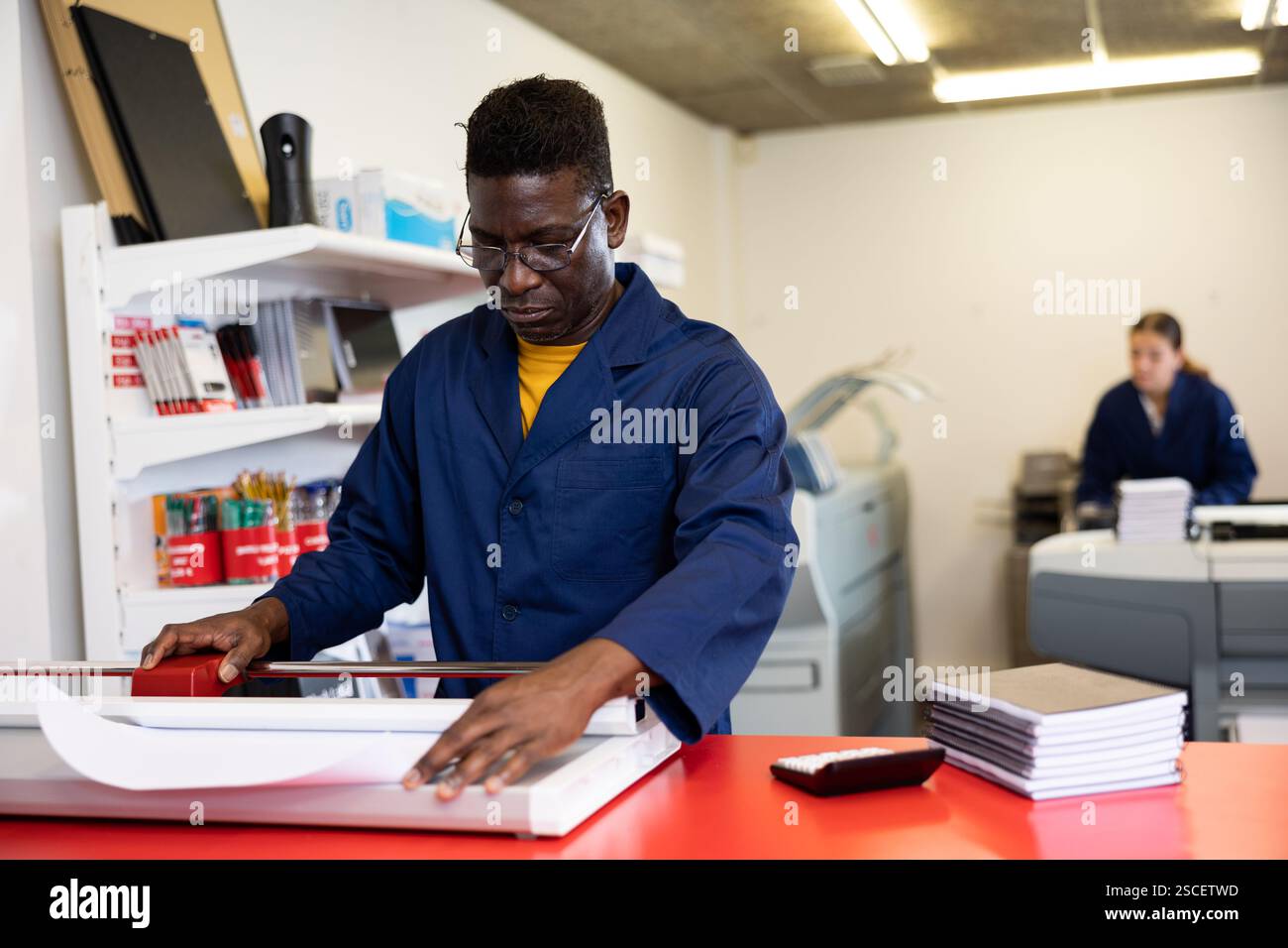 Serious print shop worker cuts paper on professional cutter Stock Photo ...