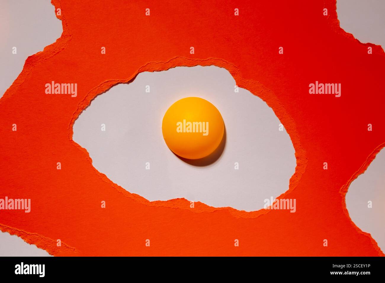 Eggs made of orange torn paper on a white background with ping pong ...