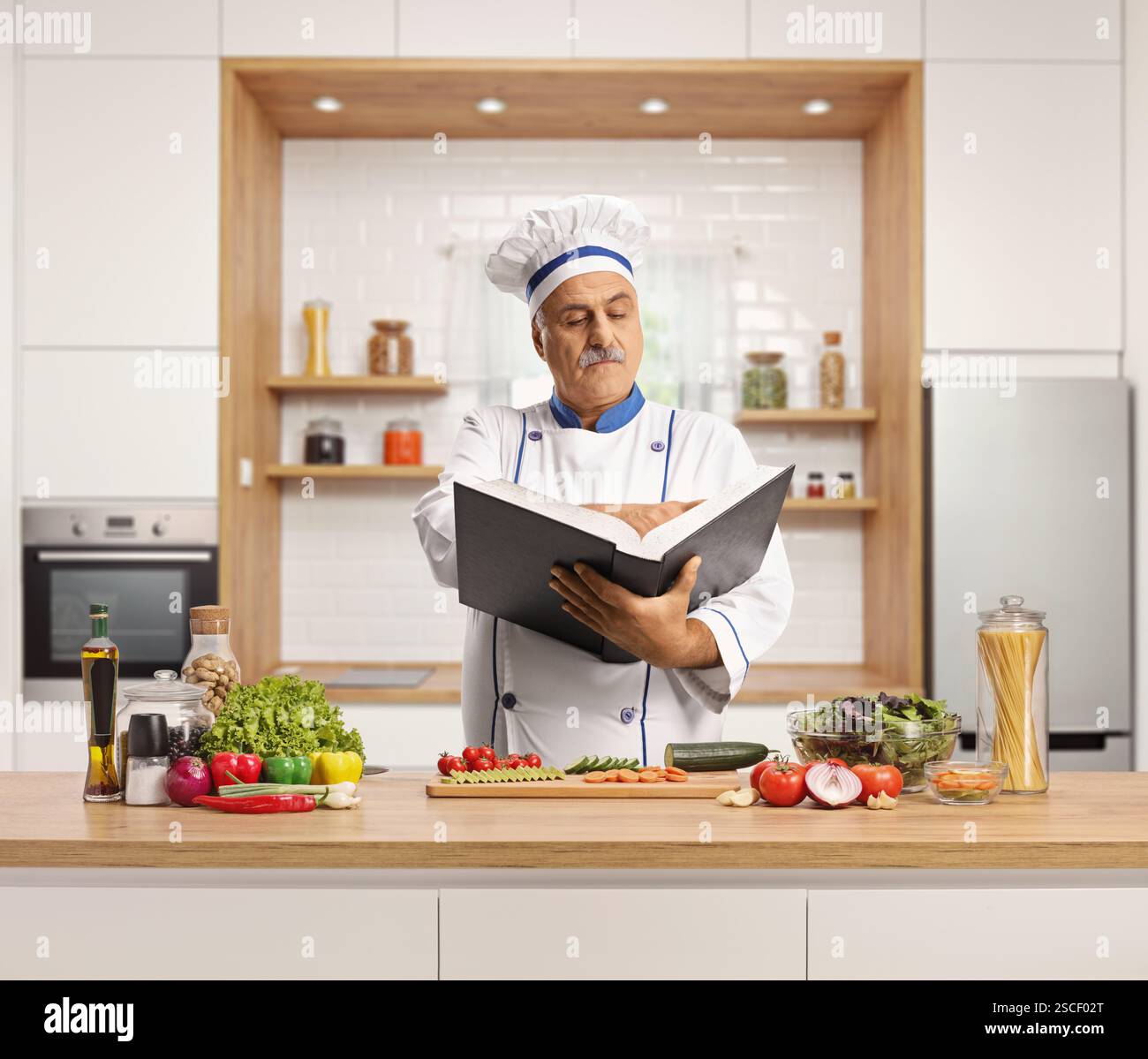 Mature male chef reading a recipe in a cook book Stock Photo - Alamy