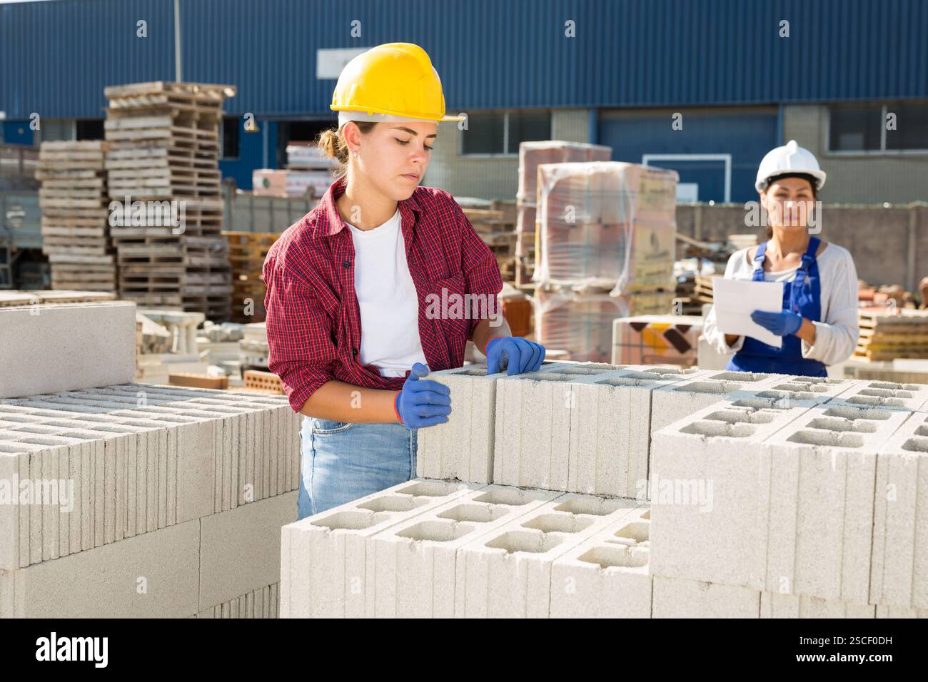 Female builders with hollow concrete blocks in outdoor warehouse Stock ...