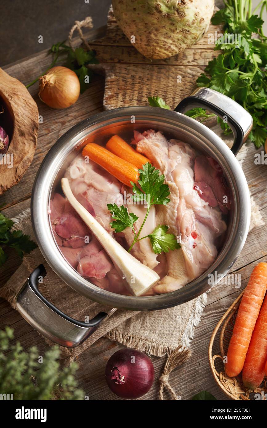 Raw chicken backs, liver and fresh vegetables in a pot of water ...
