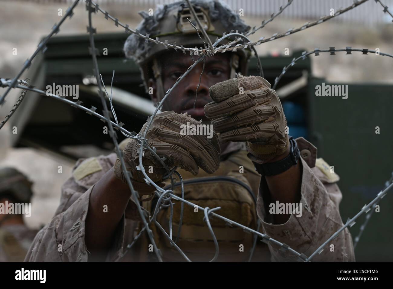 A member of the US Marine Corps installing concertina wire along the US ...