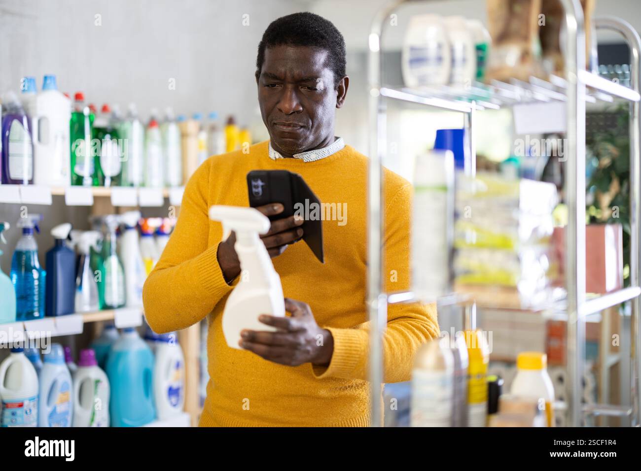 Male shopper checks QR code on spray glass cleaner for windows label in ...