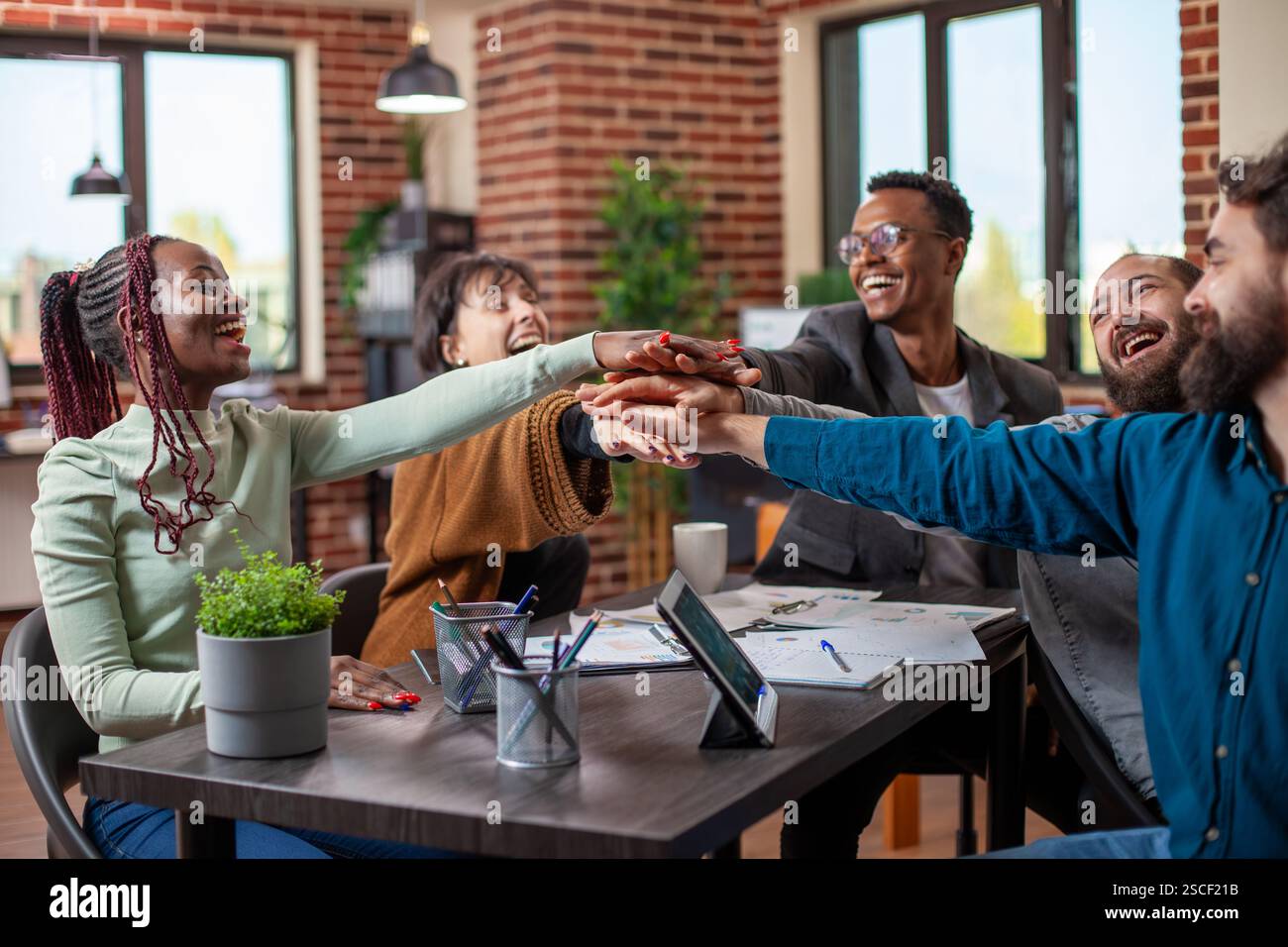Multiethnic colleagues cheerfully celebrating completion of business ...