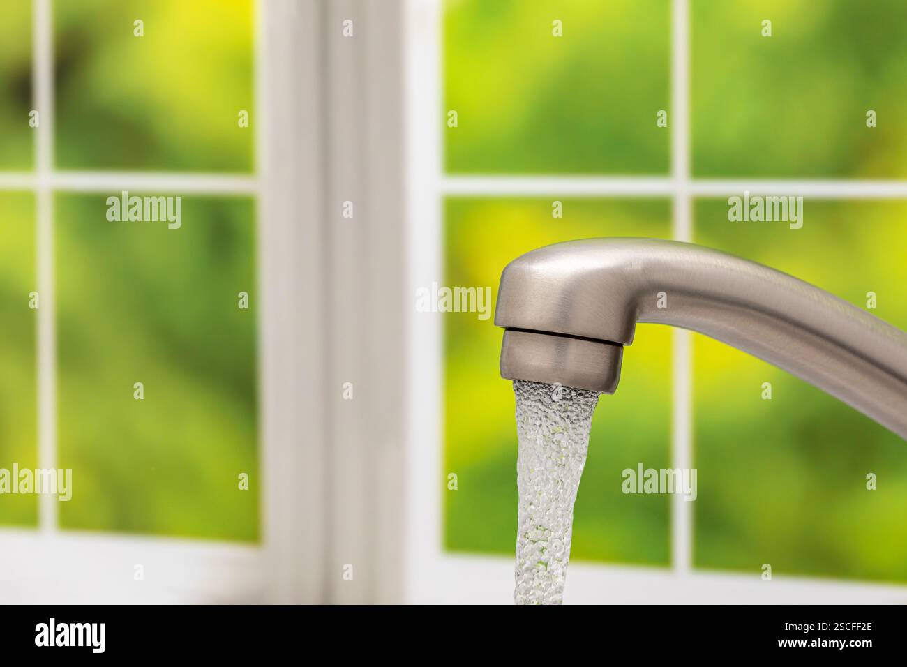 Water flowing from kitchen faucet. Water conservation, shortage and ...