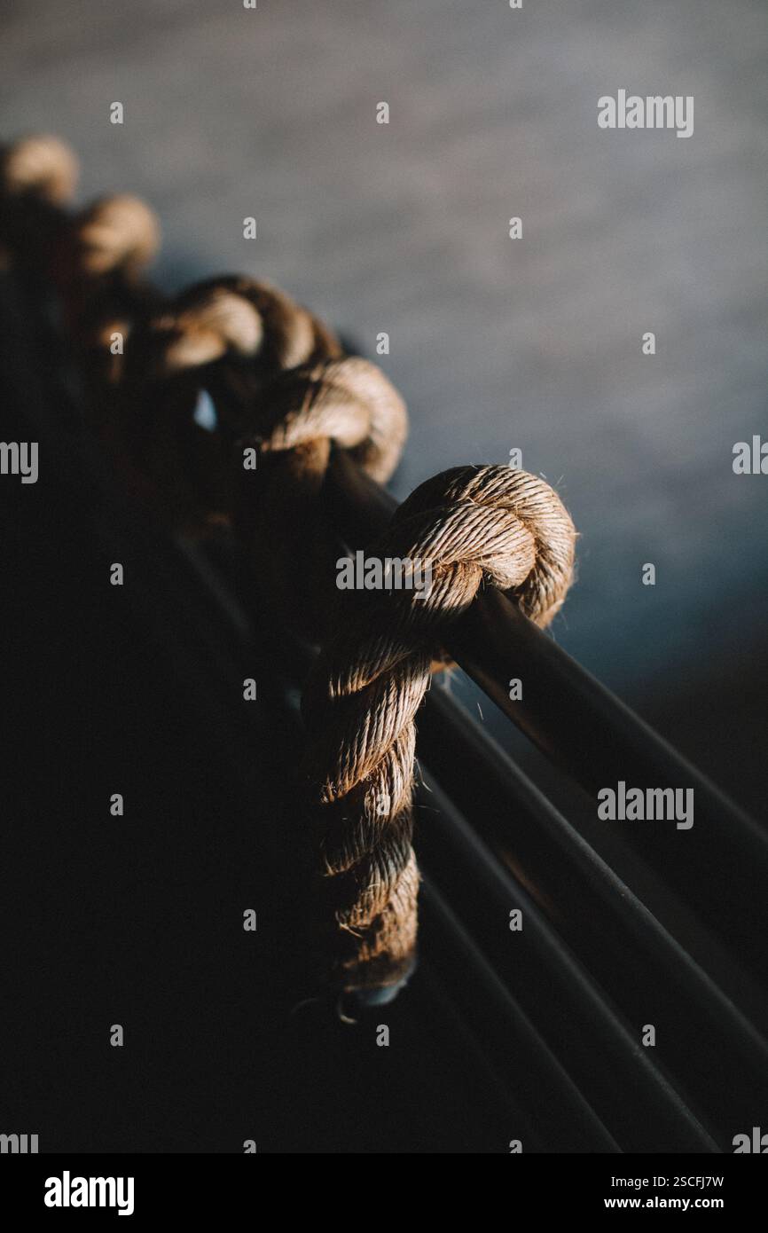 A twisted rope knot secures a wooden railing, creating an interesting ...