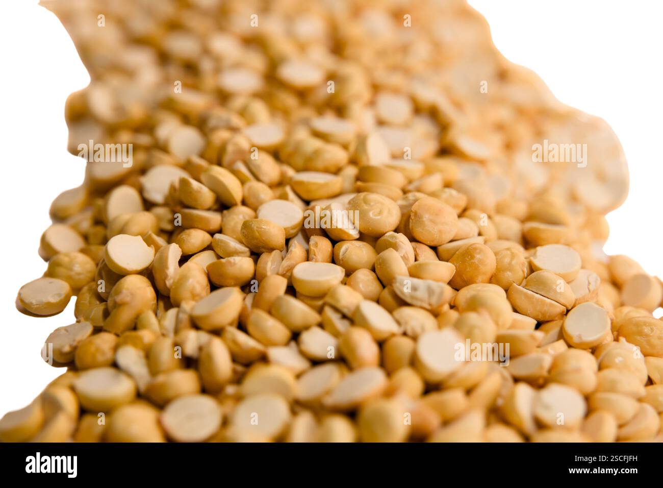 Yellow split peas are spread out across a bright white surface ...
