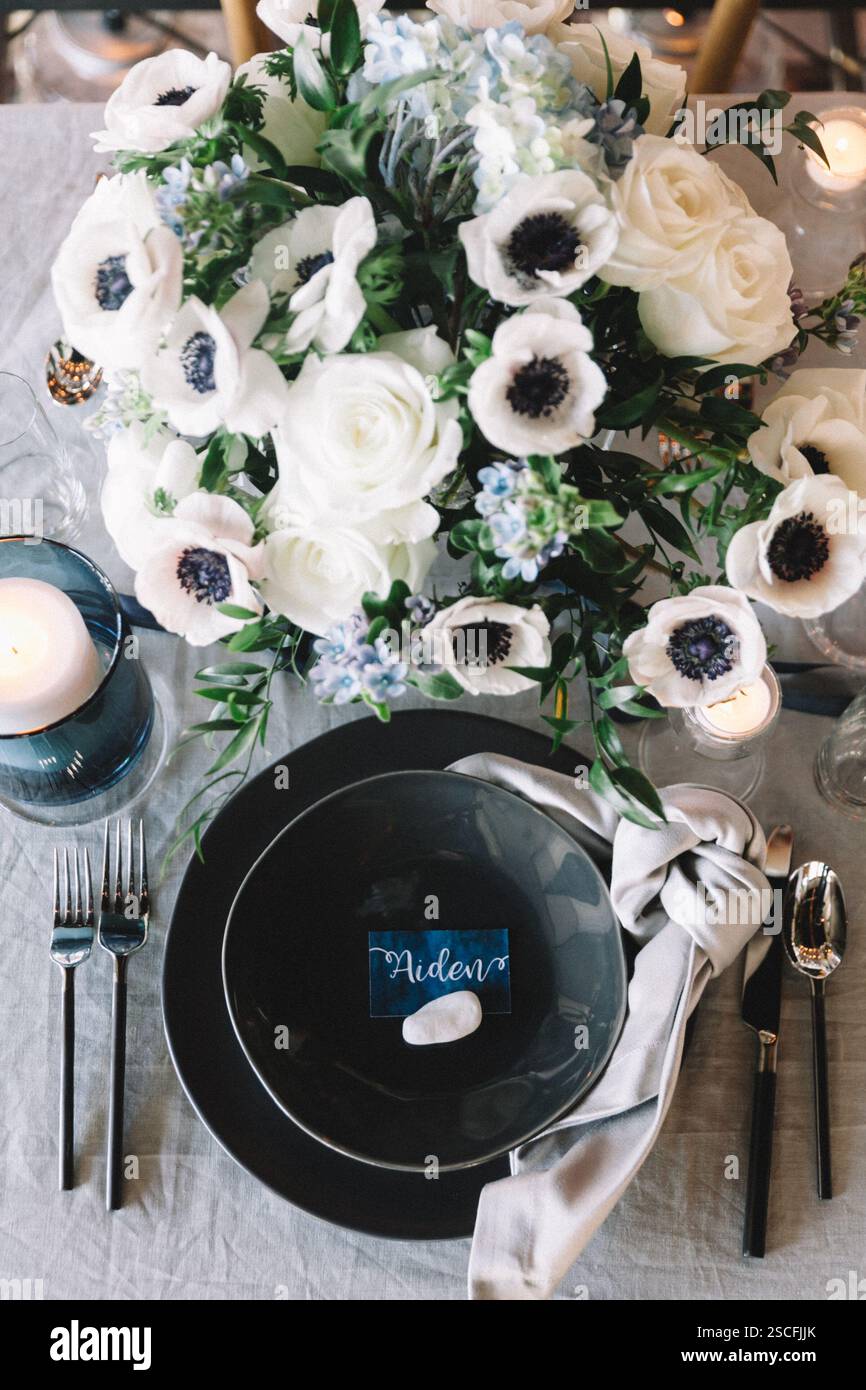 A sophisticated dining table features a dark plate with a name card and ...