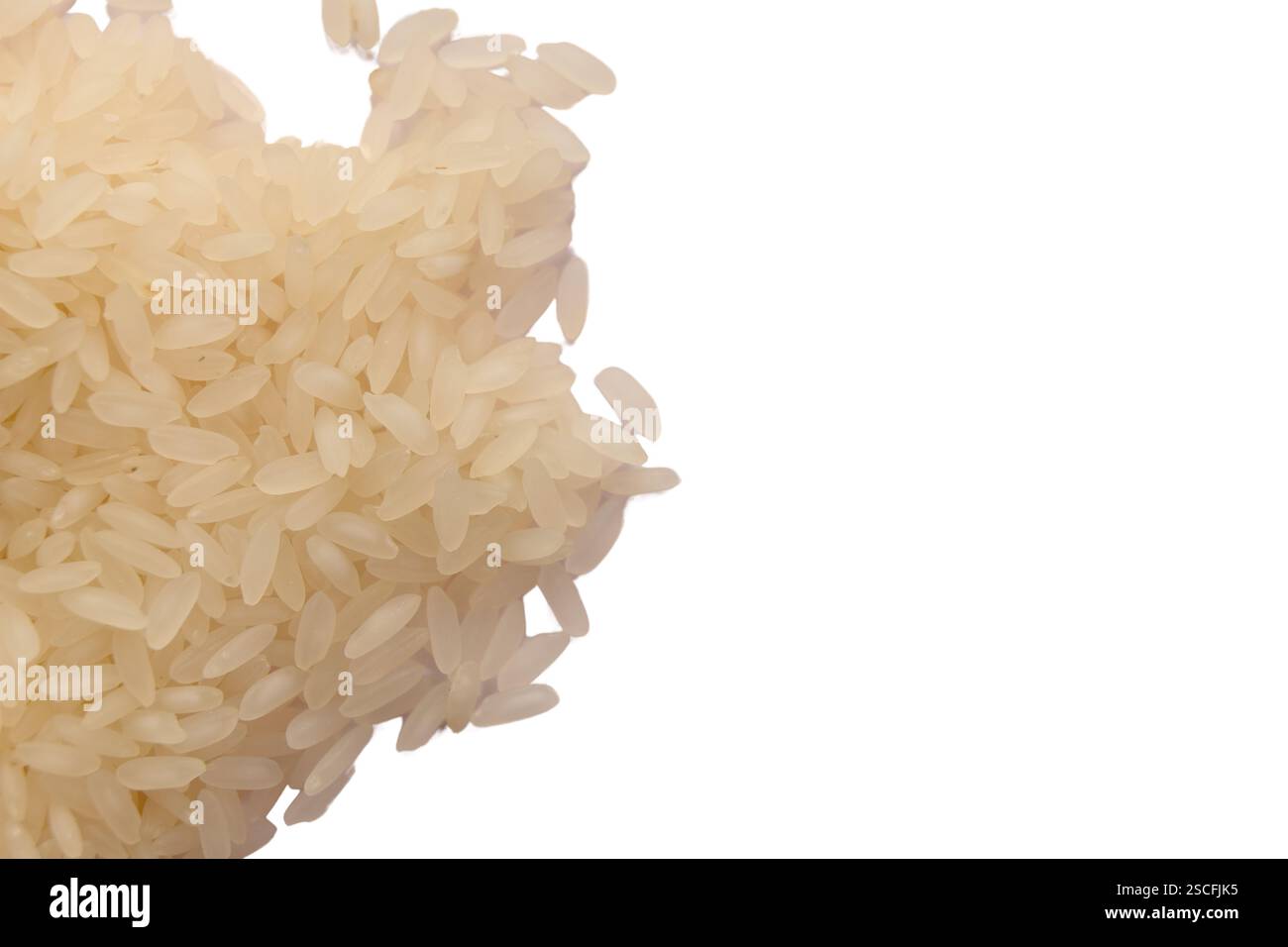 A pile of uncooked rice grains is spread lightly on a clean white ...