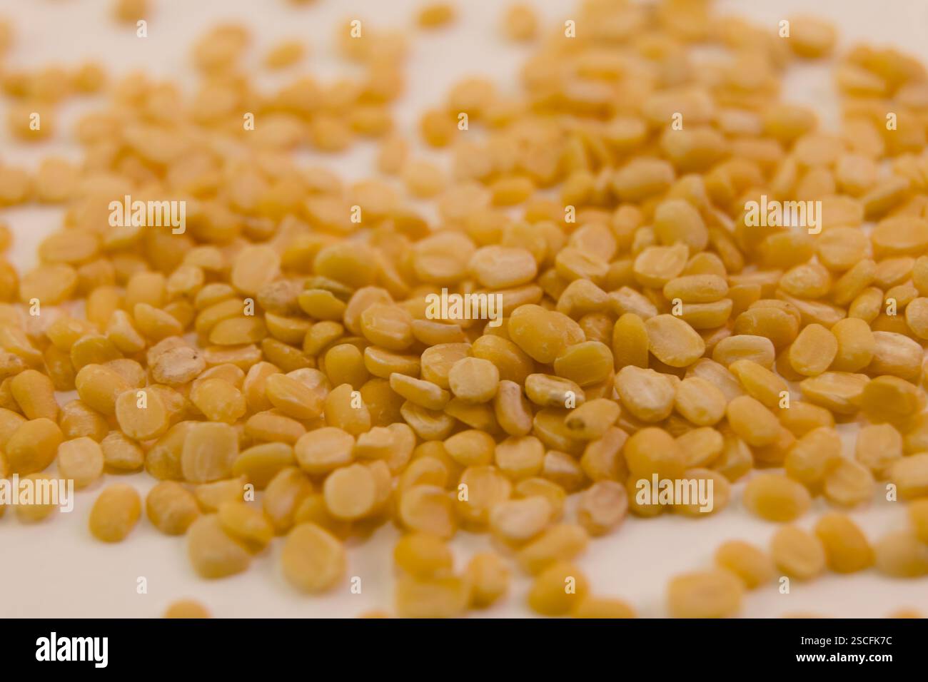 Dried yellow split peas are spread across a flat surface, showcasing ...