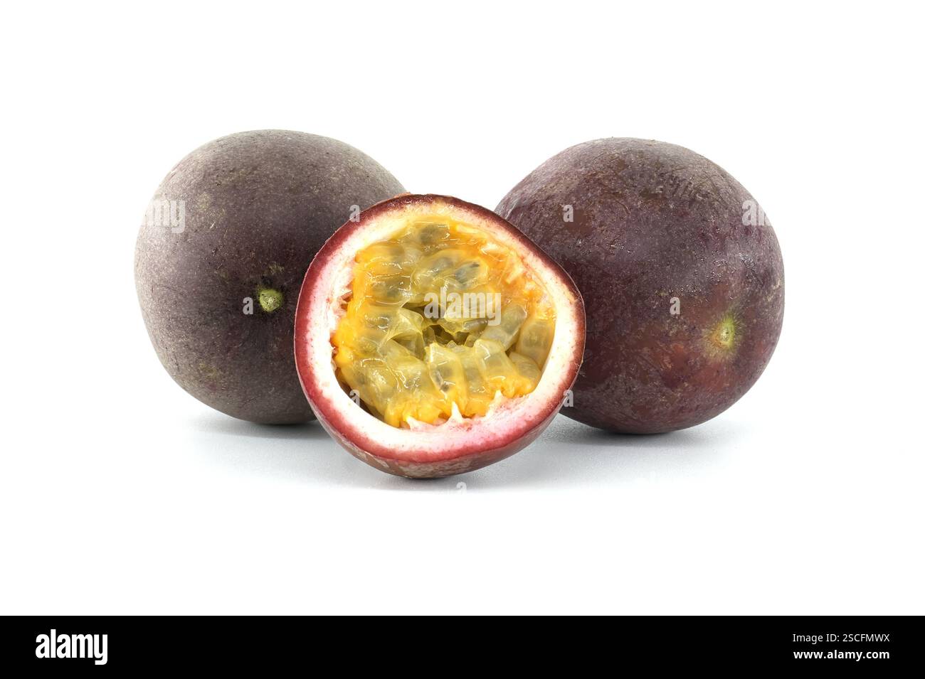Two whole passion fruits and a half showing the yellow pulp with the ...