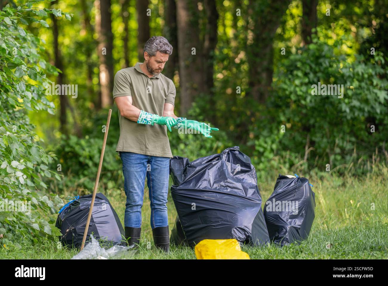 Man in rubber gloves with trash bag clean up garbage. Man collecting ...