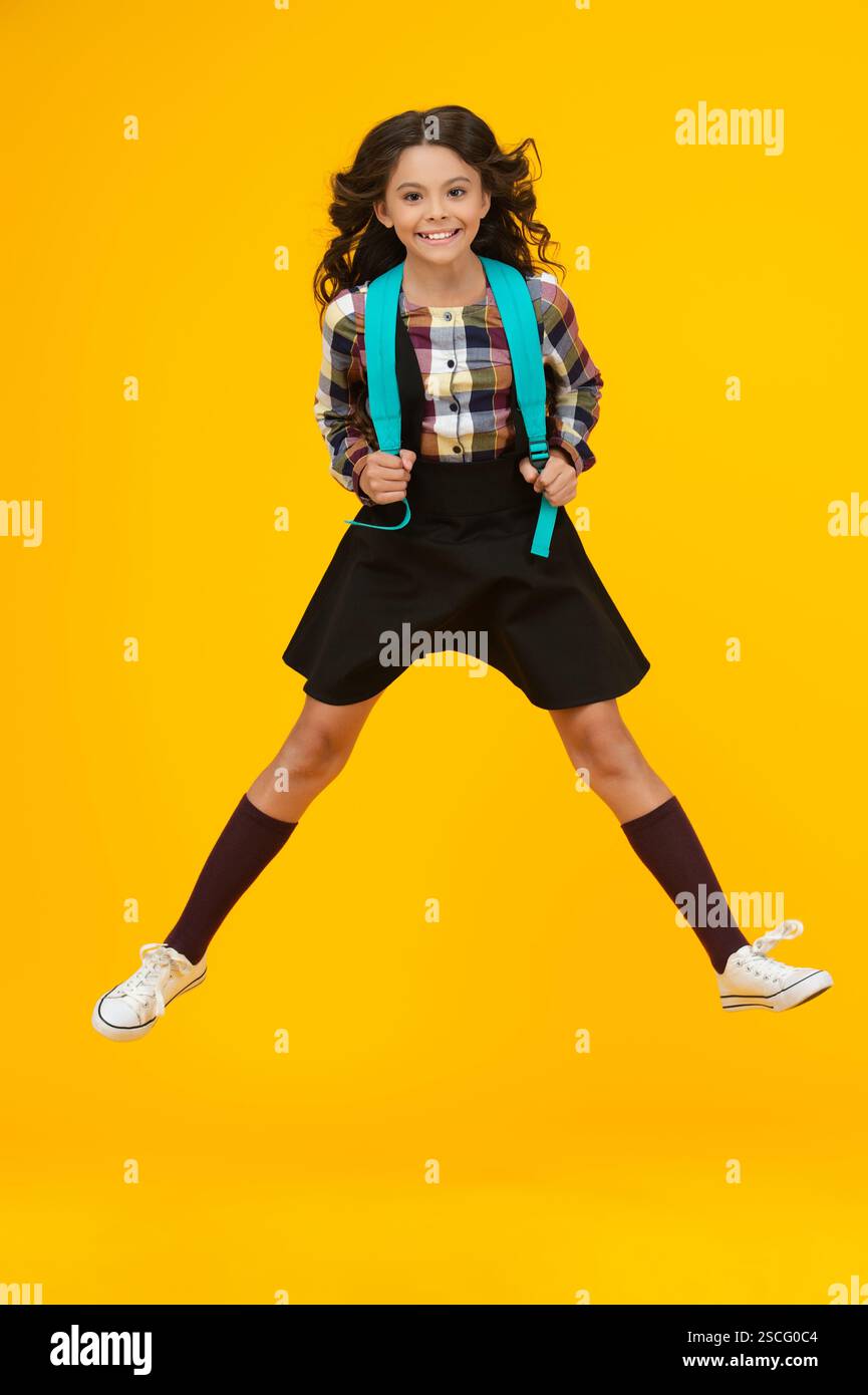 School education. Happy student. Young girl jumping isolated on yellow ...