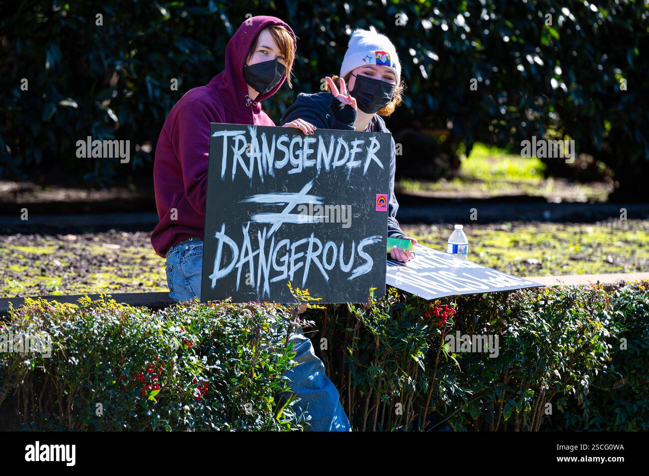 Two young people hold a Transgender does not equal dangerous sign in ...