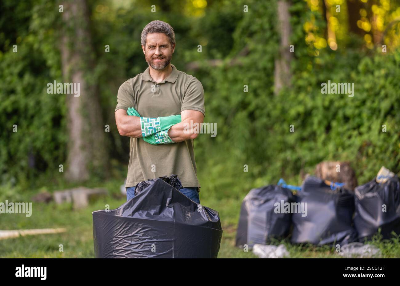 Environment plastic pollution. Volunteer man collecting garbage in forest. Environmental ...