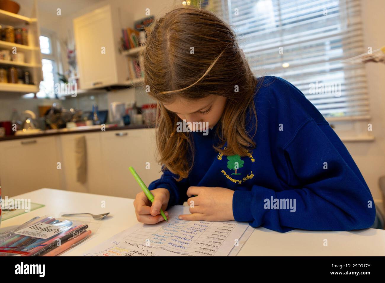 A nine year old school girl practises her spelling homework on the kitchen table at home Stock ...
