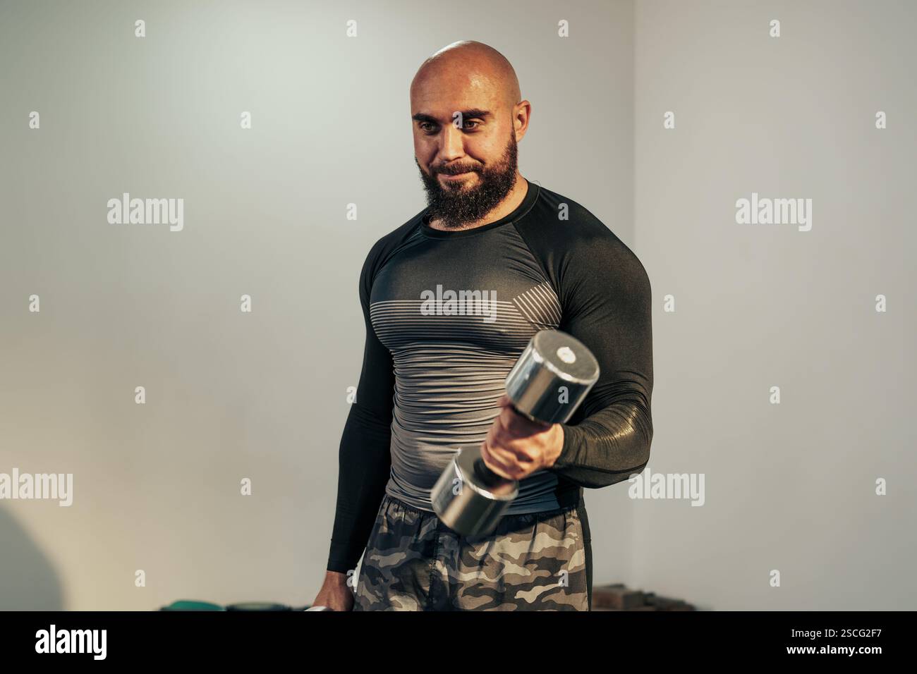 Muscular man exercising with dumbbell in a fitness studio during an ...