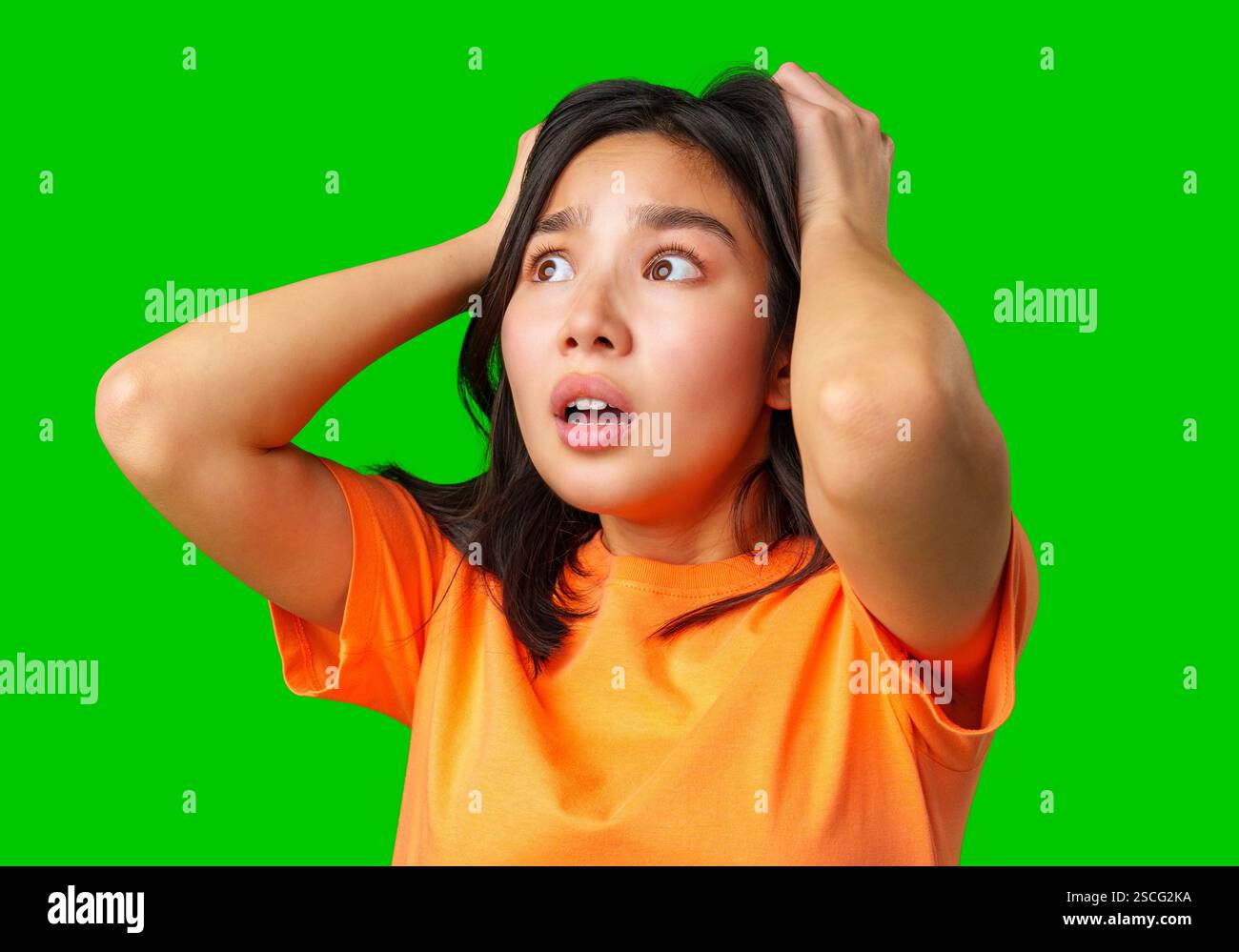 Young woman shows surprise and shock while holding her head with hands ...