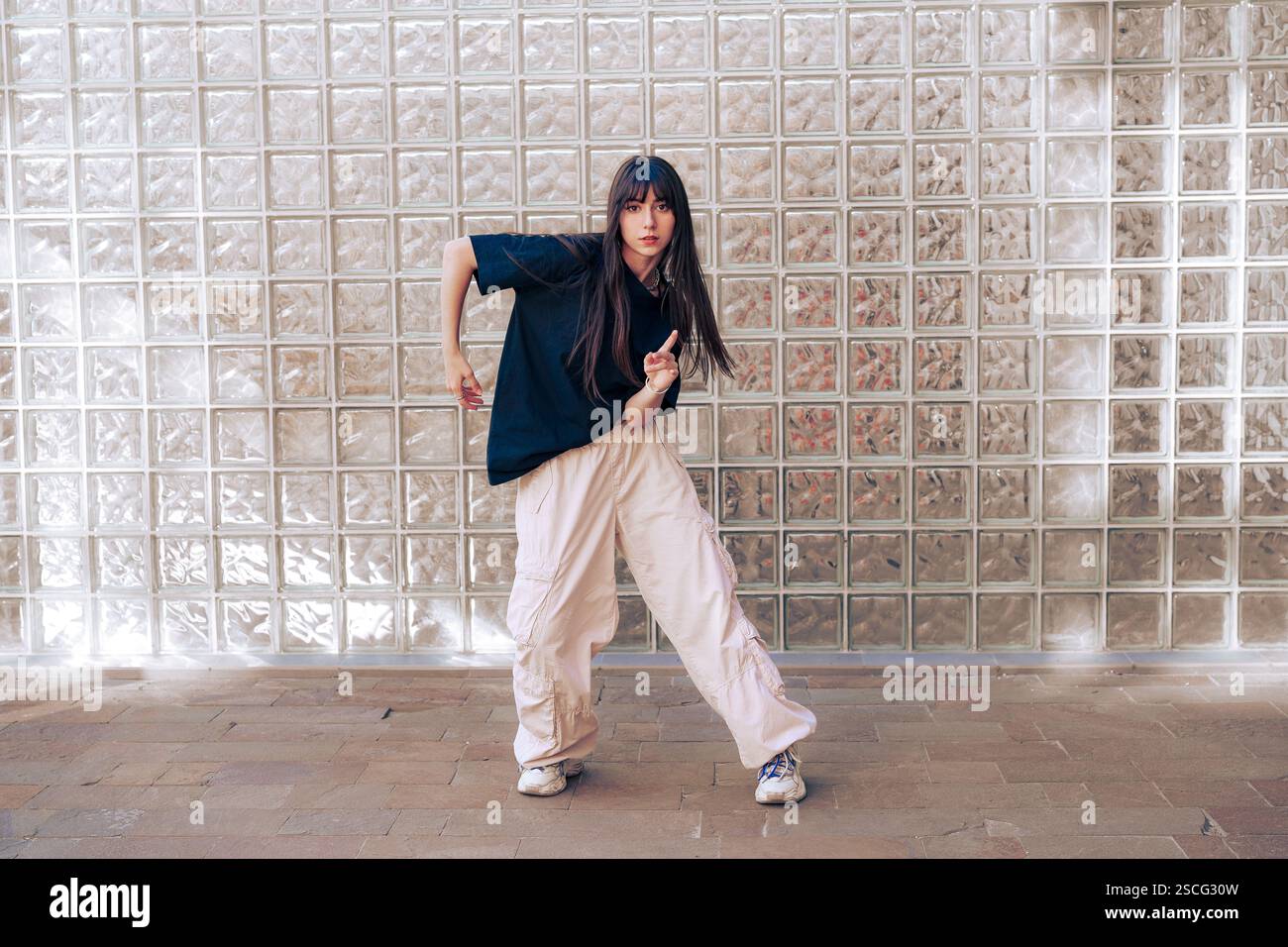 Young dancer performs expressive moves against glass block wall in ...