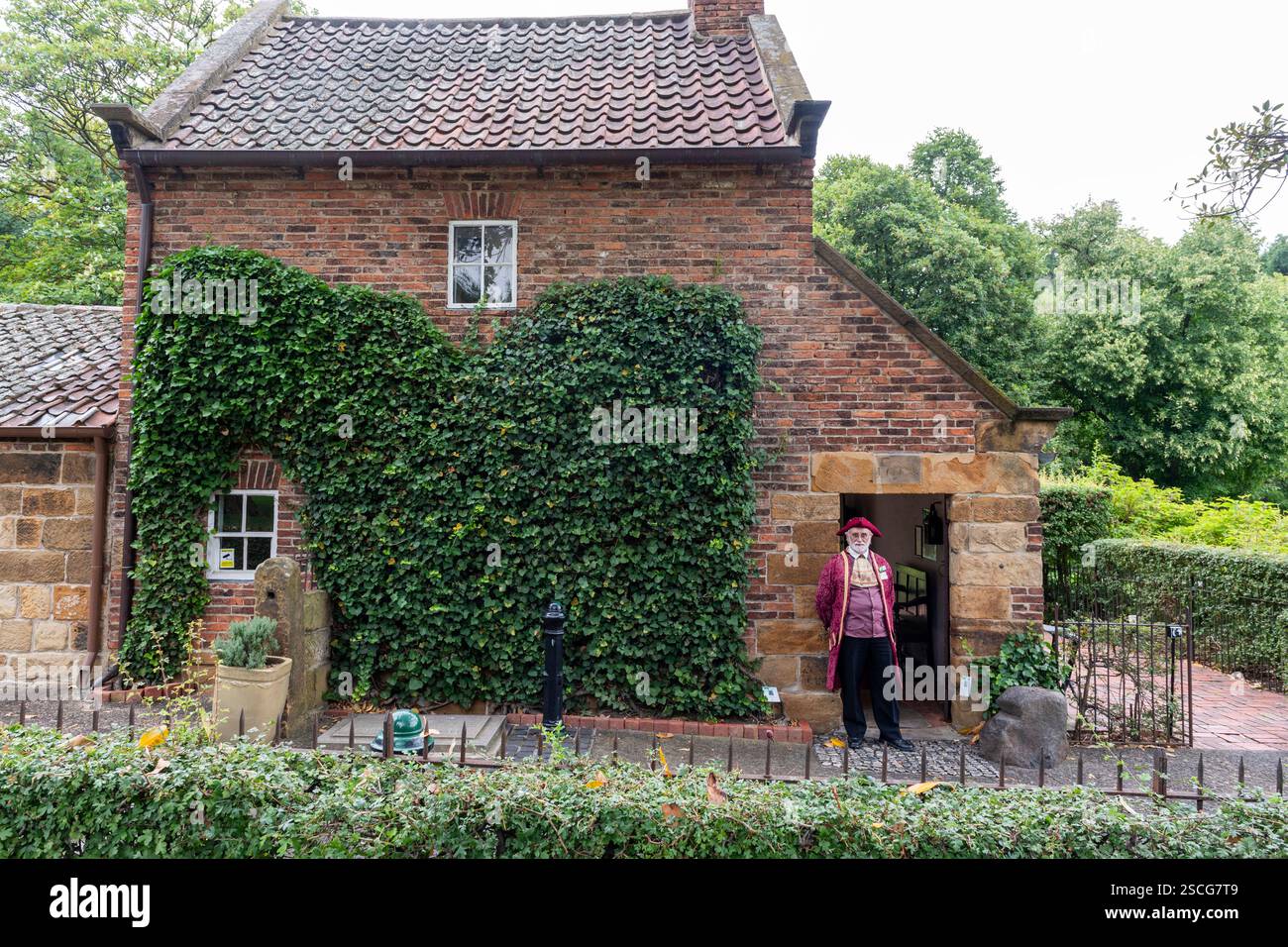 A man in period costume of 1700s stands in front of Cook's Cottage, the ...