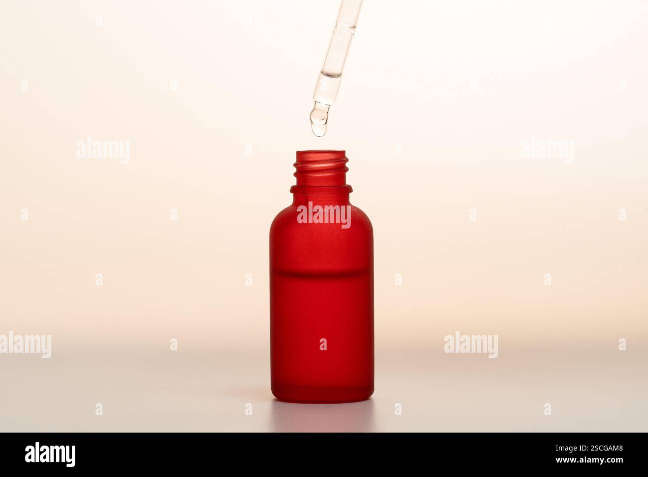 A drop on the end of the pipette of the red dropper bottle wuth face ...