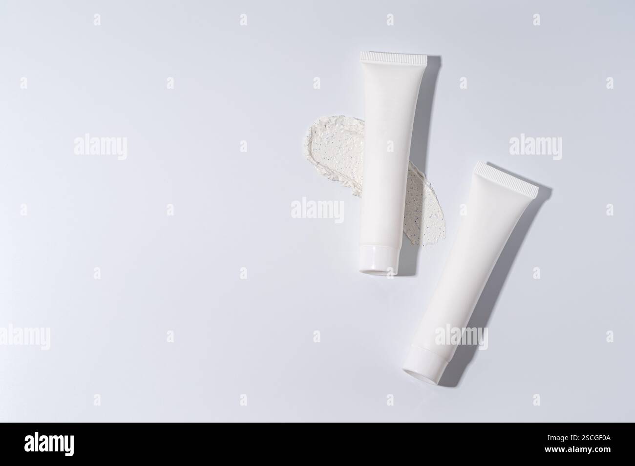 Mockup white tubes of cream for face lying on texture of scrub smear ...