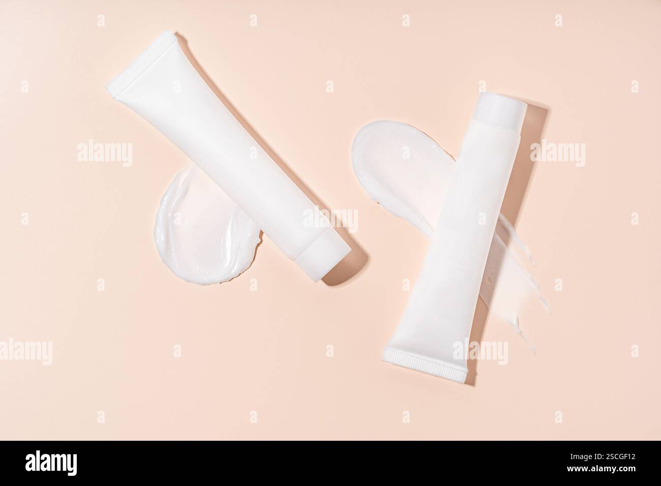 Mockup white tubes of cream for face lying on texture of smear, product ...