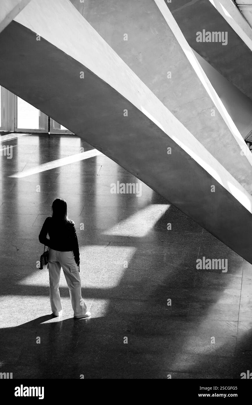 Woman standing inside modern building with shadows forming geometrical ...
